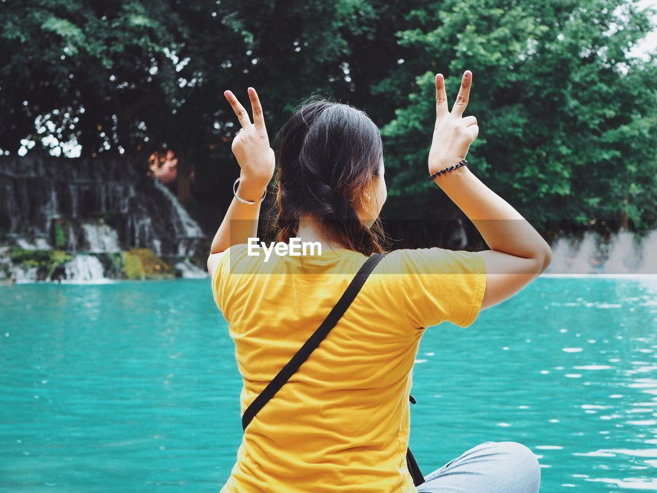 Rear view of woman gesturing peace sign | ID: 129107678
