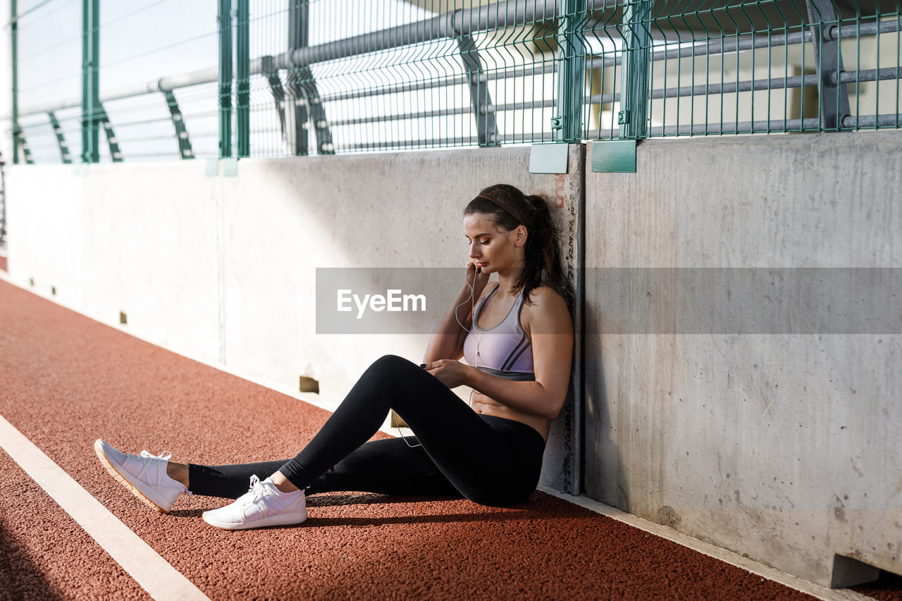 Young woman sitting on running track | ID: 110745116