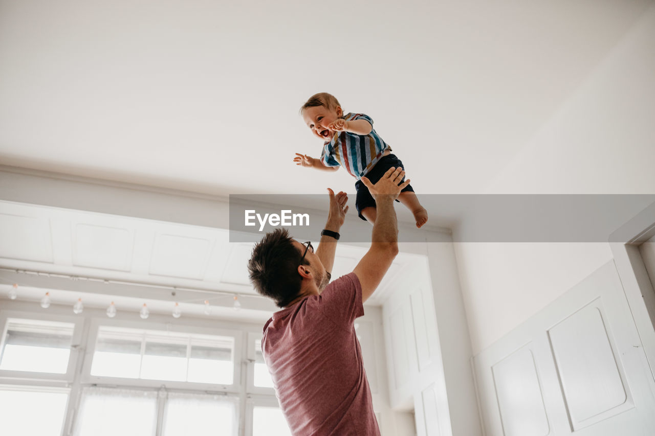 Low angle view of playful father catching | ID: 125140355