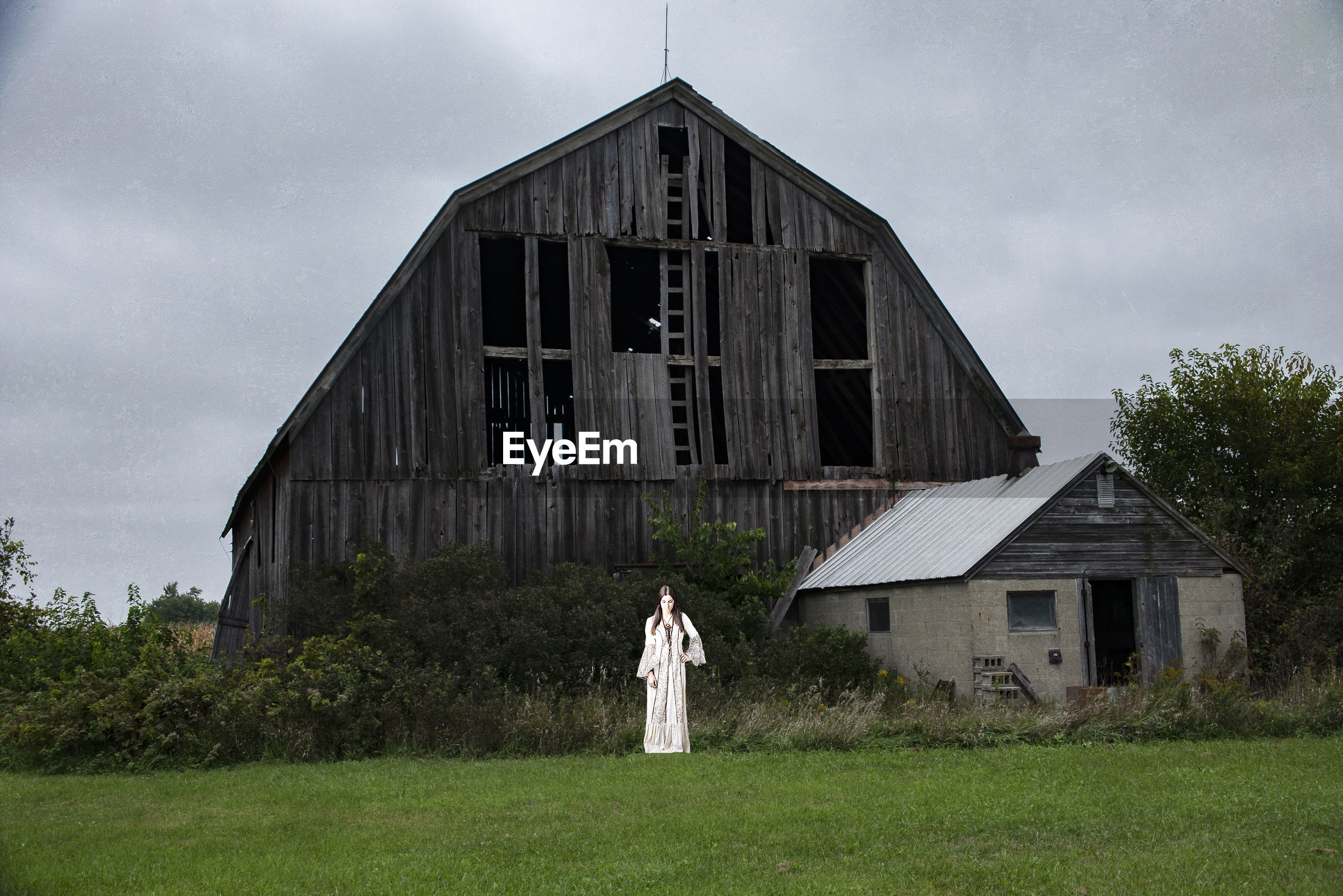 Woman standing against abandoned barn | ID: 129559030