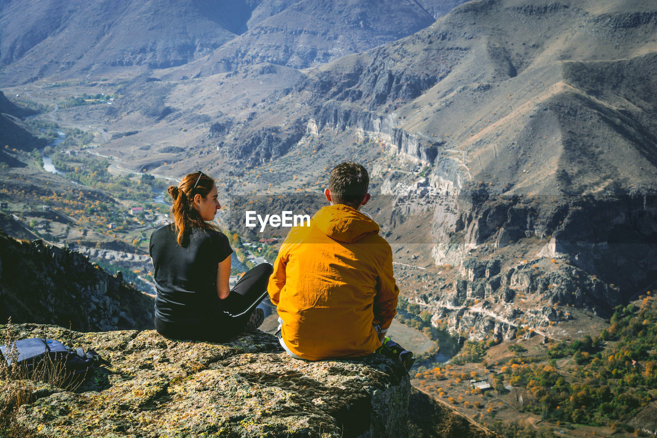 Rear view of couple sitting on cliff | ID: 150117651