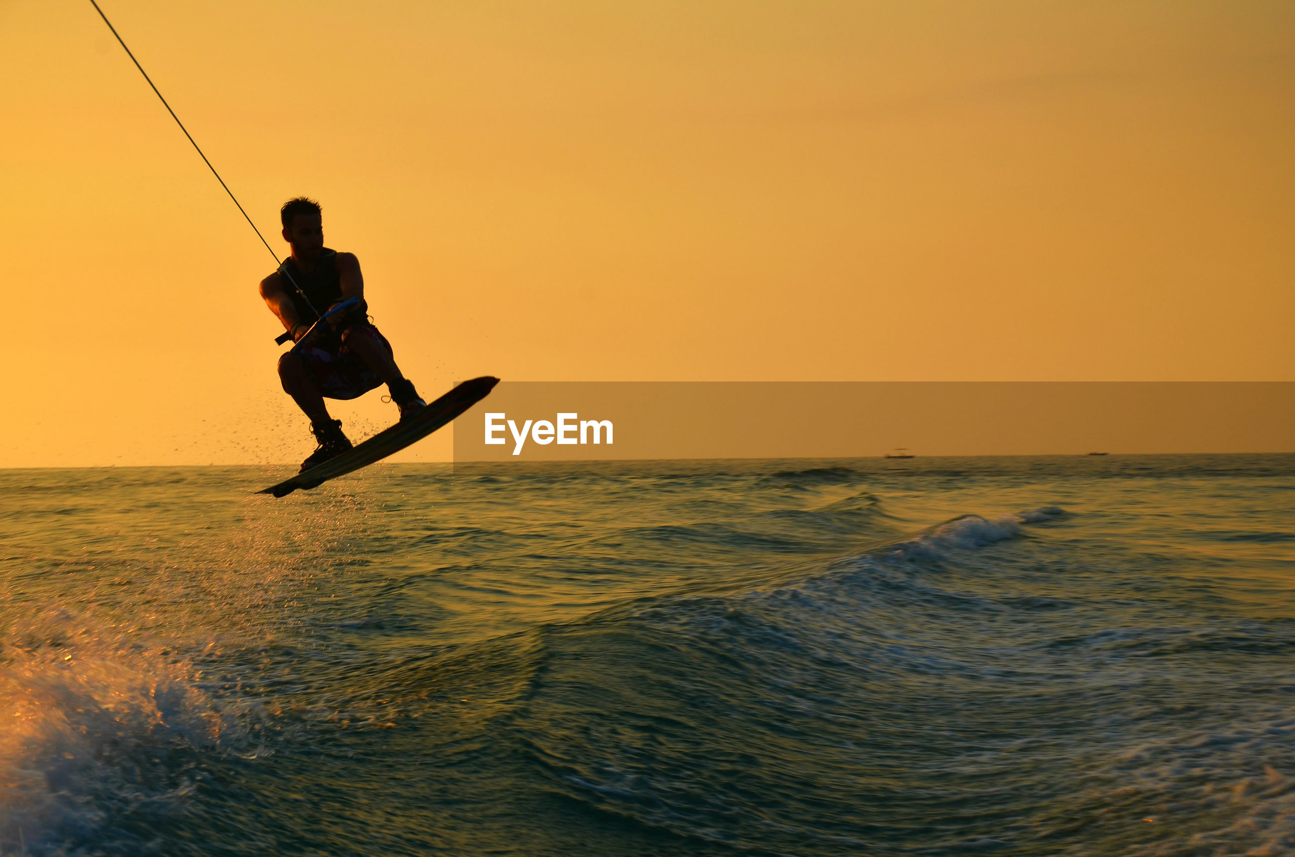 Man wakeboarding at sunset | ID: 84190918