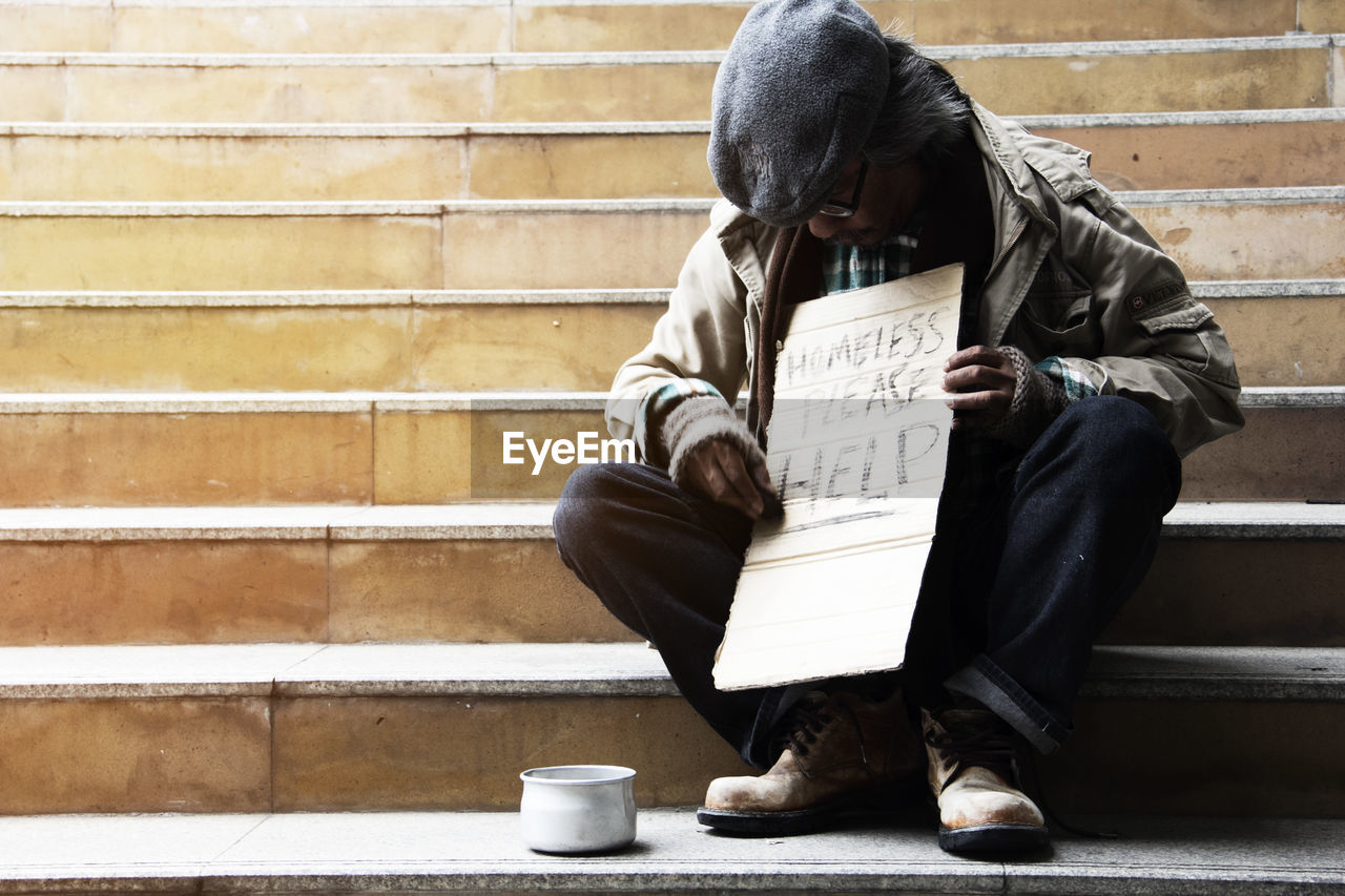 Male beggar begging while sitting on steps | ID: 119399734