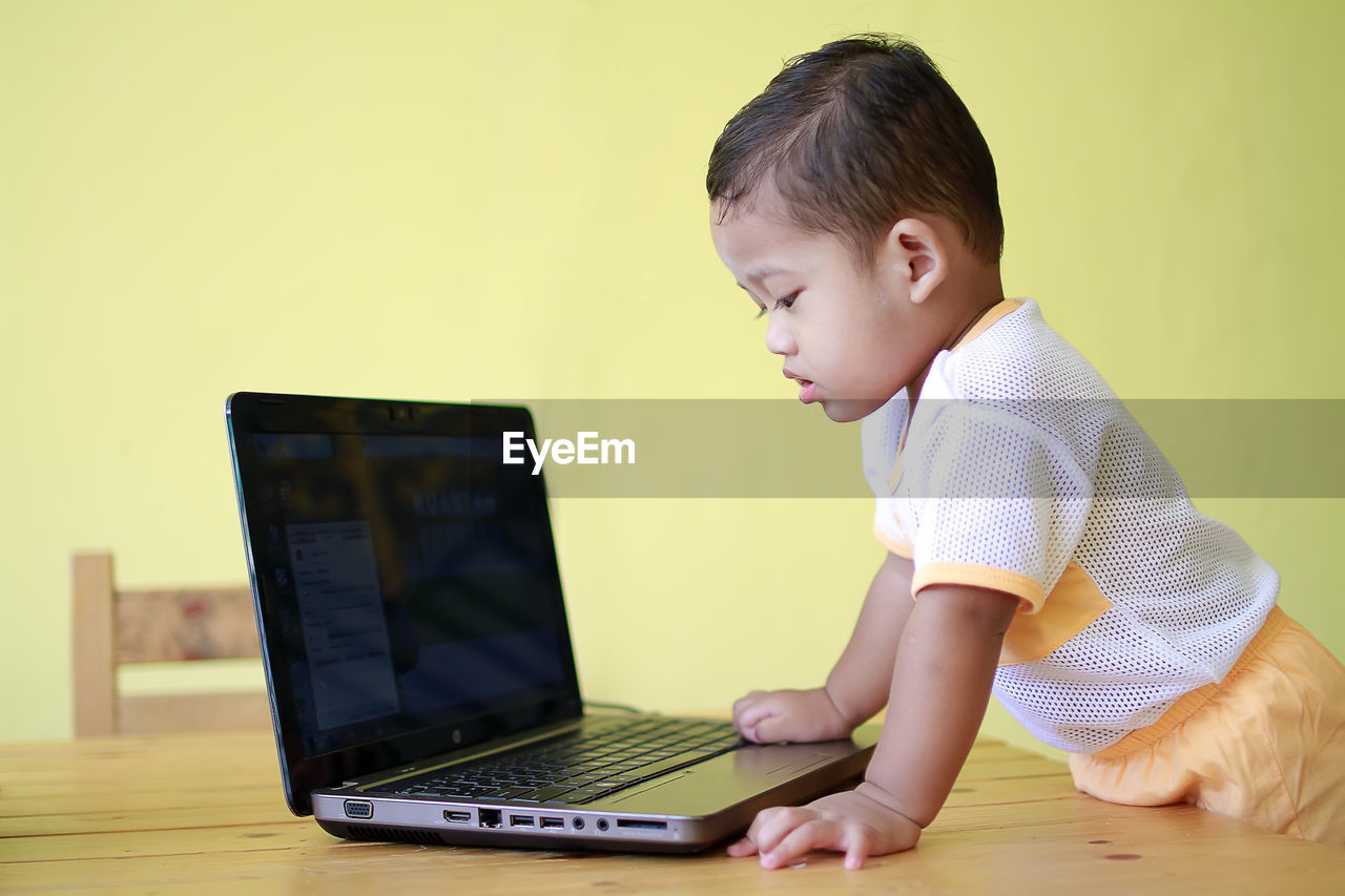 Side view of boy using laptop at table | ID: 111861944
